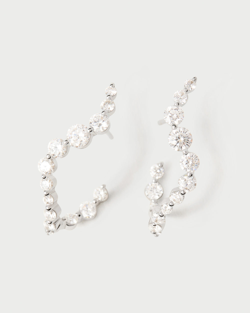 Elegant semi hoops in 18K white gold featuring an undulating line o ...